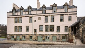 Um edifício histórico com várias janelas e portas, fachada de pedra e estilo arquitetônico tradicional.