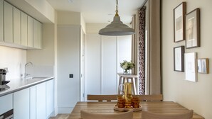 Uma cozinha moderna com armários brancos, uma mesa de jantar de madeira e uma luminária pendente.
