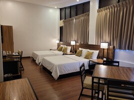 Quarto de hotel com duas camas, uma mesa de jantar e um pequeno espaço de estar.