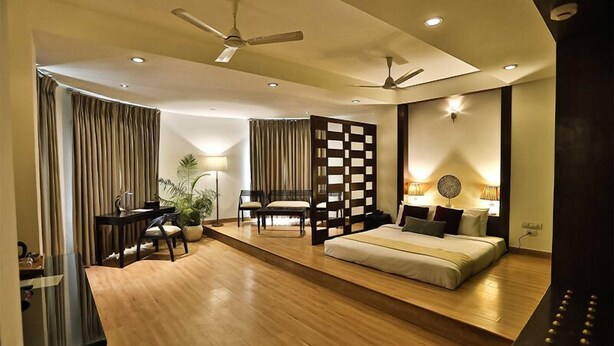 Quarto de hotel moderno com uma cama grande, uma escrivaninha, uma cadeira e um vaso de planta.