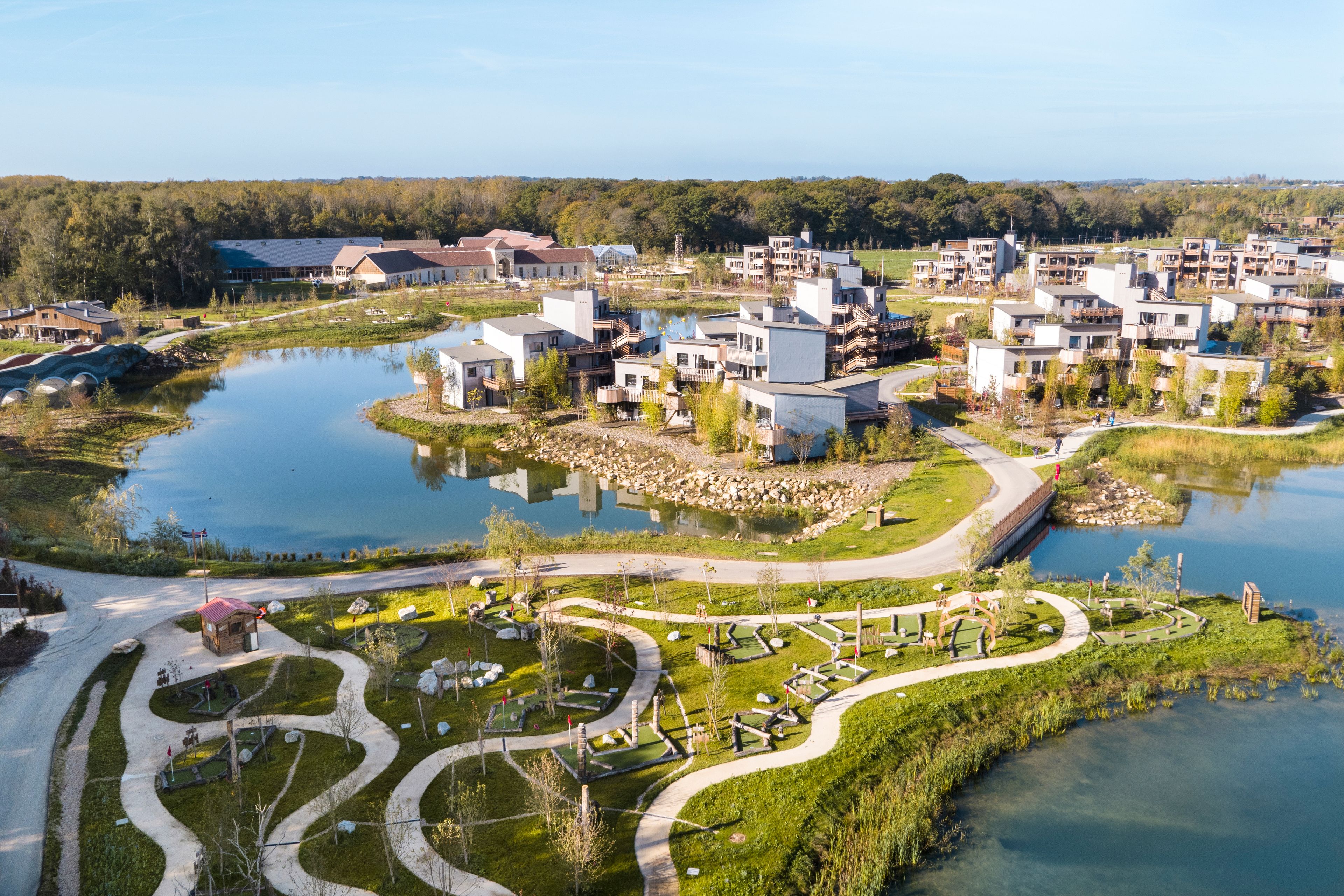 Uma área residencial moderna com um elemento central de água, cercada por habitações contemporâneas e um parque bem cuidado.