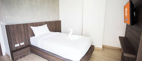 Quarto de hotel moderno com cabeceira de madeira, colcha branca e travesseiro em forma de cisne.