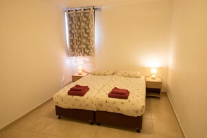 Quarto com uma cama, duas mesas de cabeceira e uma janela com cortinas.