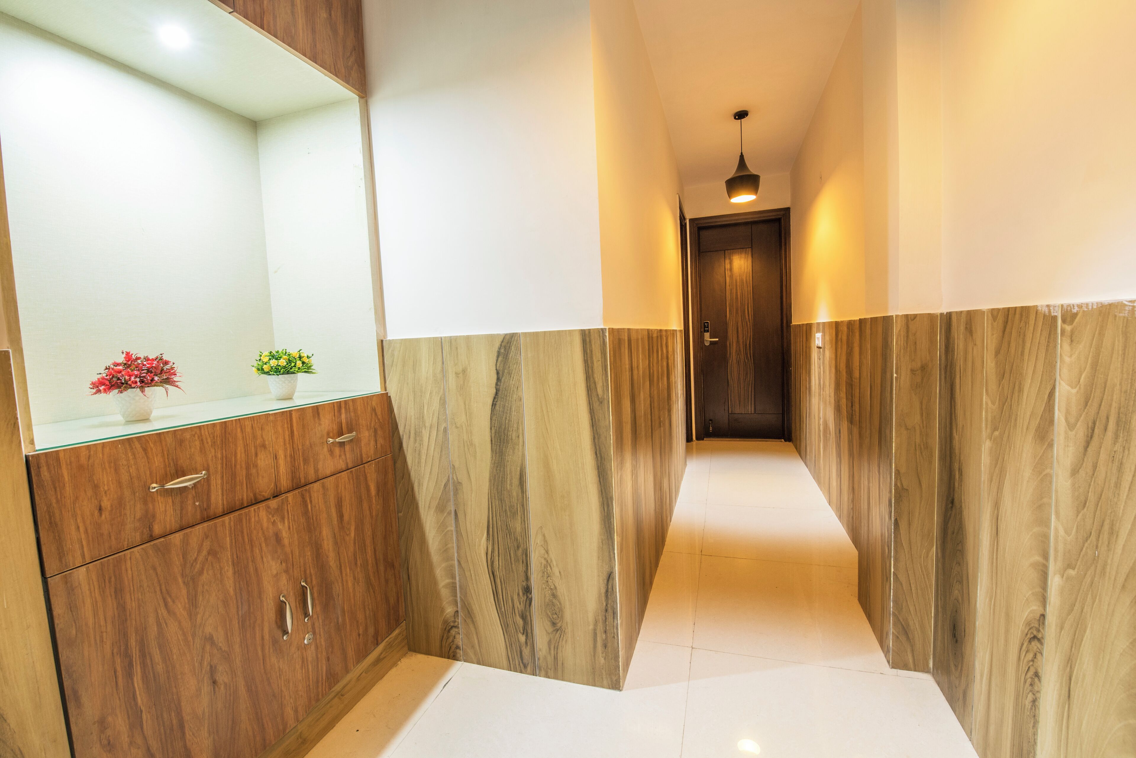 Um corredor com um armário de madeira, um espelho e uma porta no final.
