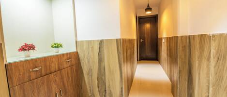 Um corredor com um armário de madeira, um espelho e uma porta no final.