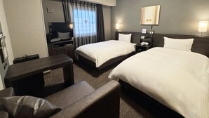 Quarto de hotel com duas camas, televisão, escrivaninha e uma cadeira.