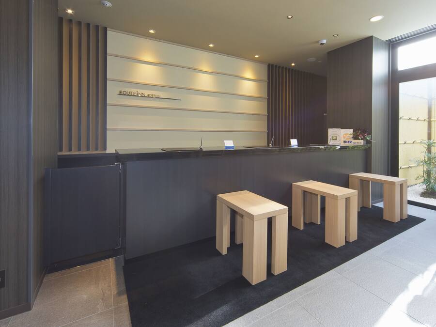 Uma área de recepção de hotel moderna, com um balcão escuro, banquetes de madeira e uma placa com a inscrição "Equite Inn Hotels".