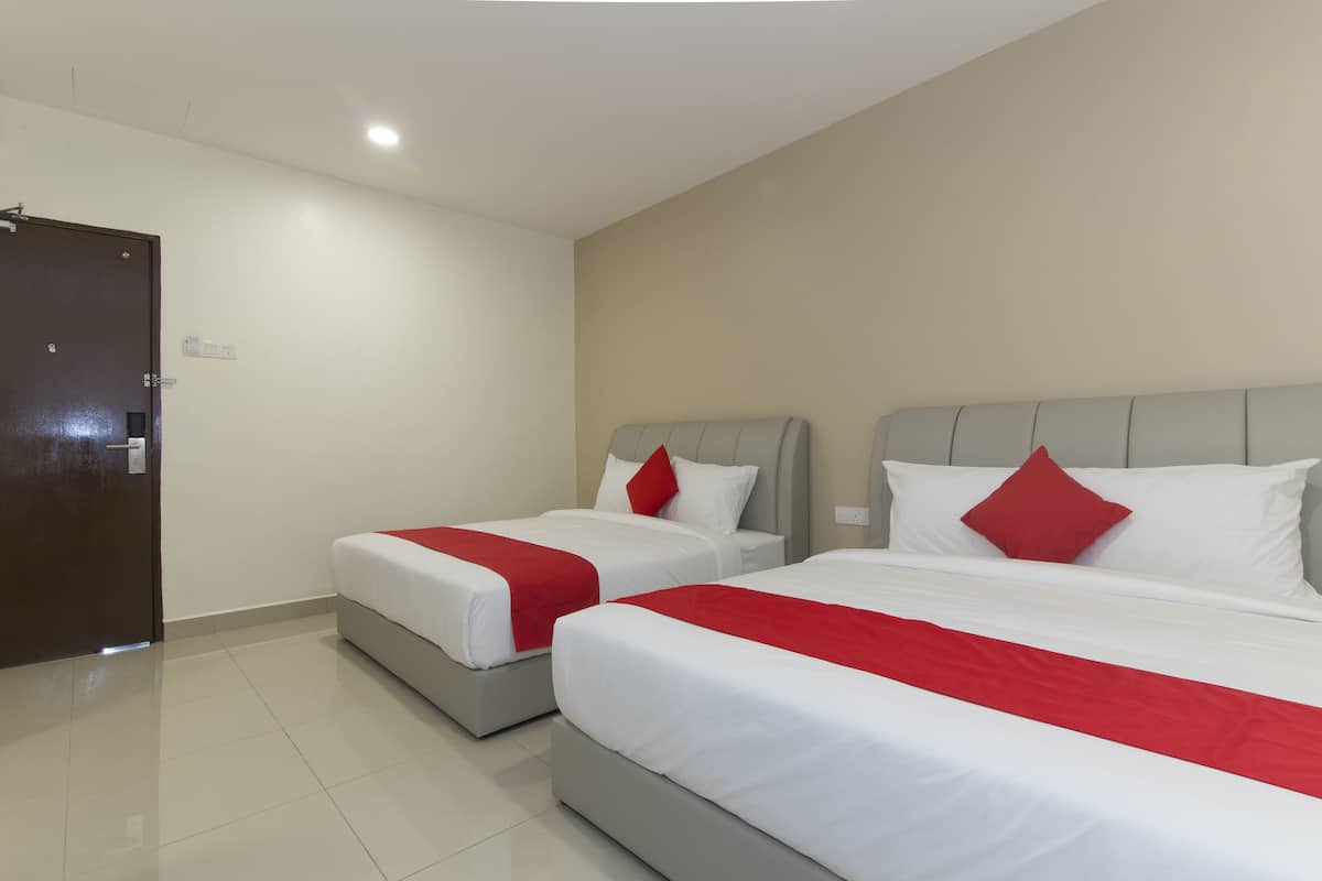 Quarto de hotel com duas camas, cada uma com roupa de cama branca e detalhes vermelhos, cabeceira cinzenta e porta marrom.