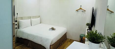 Quarto moderno com cama, mesa de cabeceira e um vaso de planta.