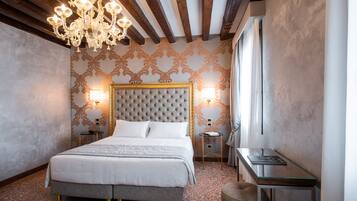 Quarto com cabeceira estofada, uma cama grande, um candelabro, uma mesa de cabeceira e um banquinho redondo.