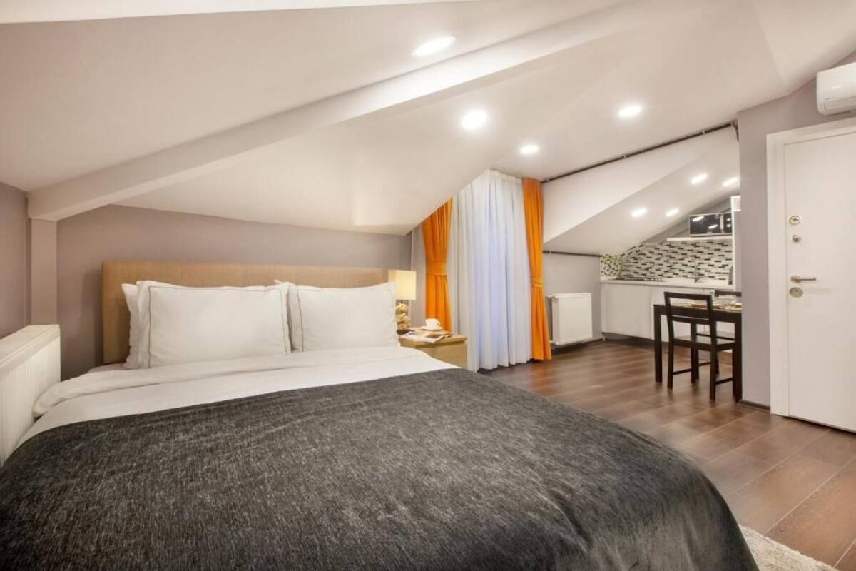 Quarto com uma cama grande, uma escrivaninha e uma escada que leva a um andar superior.