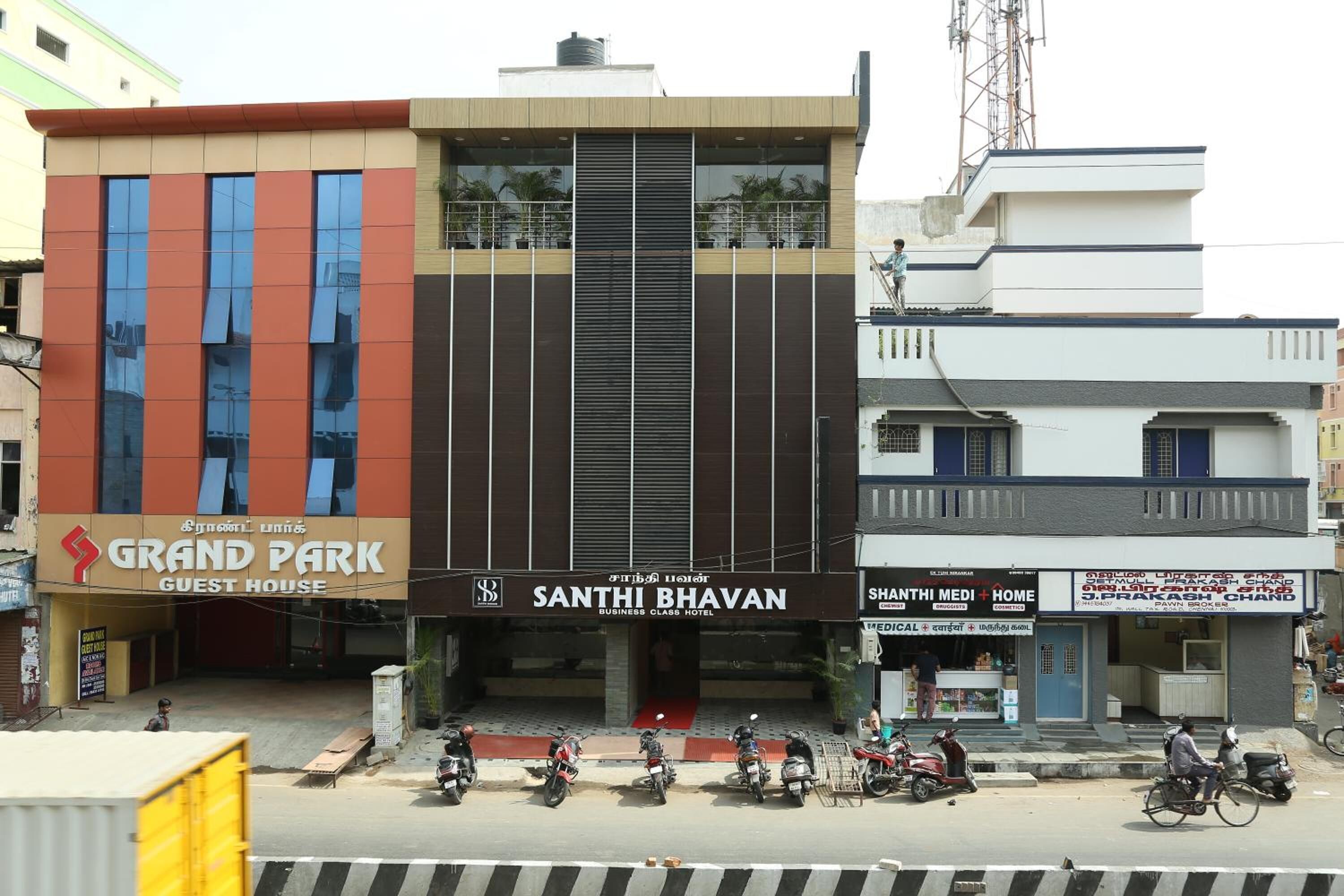 Um edifício com placas indicando 'Grand Park Guest House' e 'Santhi Bhavan Business Class Hotel'.