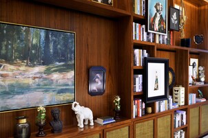 Uma estante de madeira com livros, quadros emoldurados e objetos decorativos.