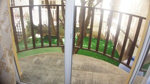 Uma varanda com vista para um gramado verde e árvores.