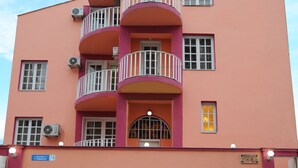 Um edifício de vários andares com varandas, aparelhos de ar condicionado e uma placa de rua indicando o endereço.