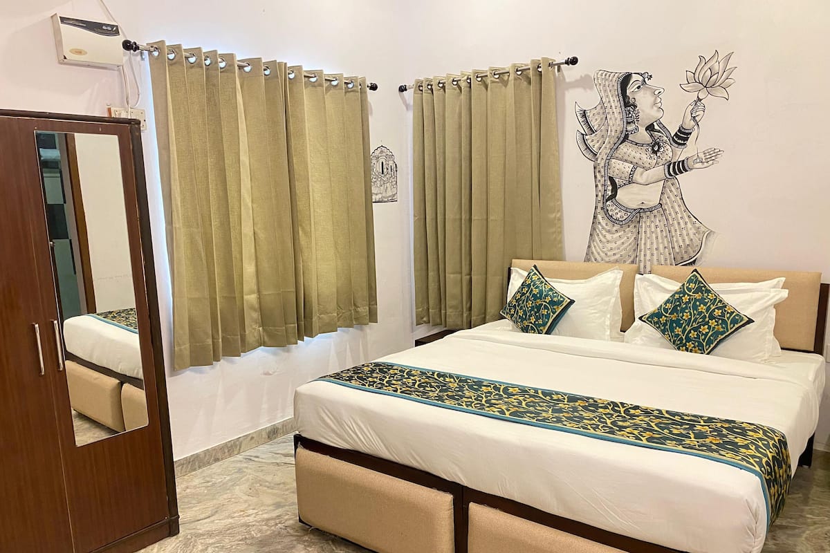 Quarto de hotel com cama, cortinas, espelho e um ornamento na parede.
