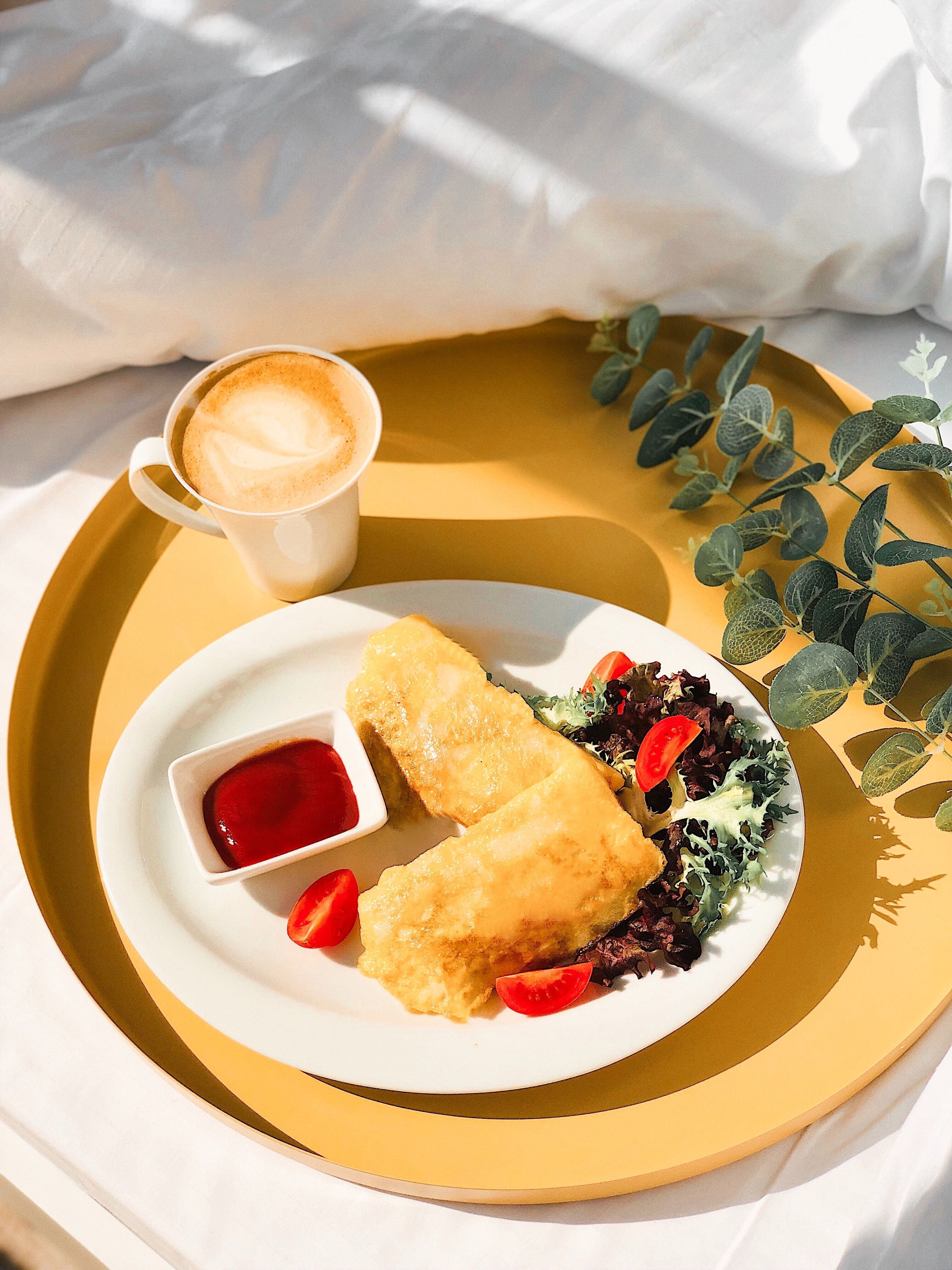 Uma bandeja com um prato de peixe frito, uma xícara de café e uma pequena tigela de molho.