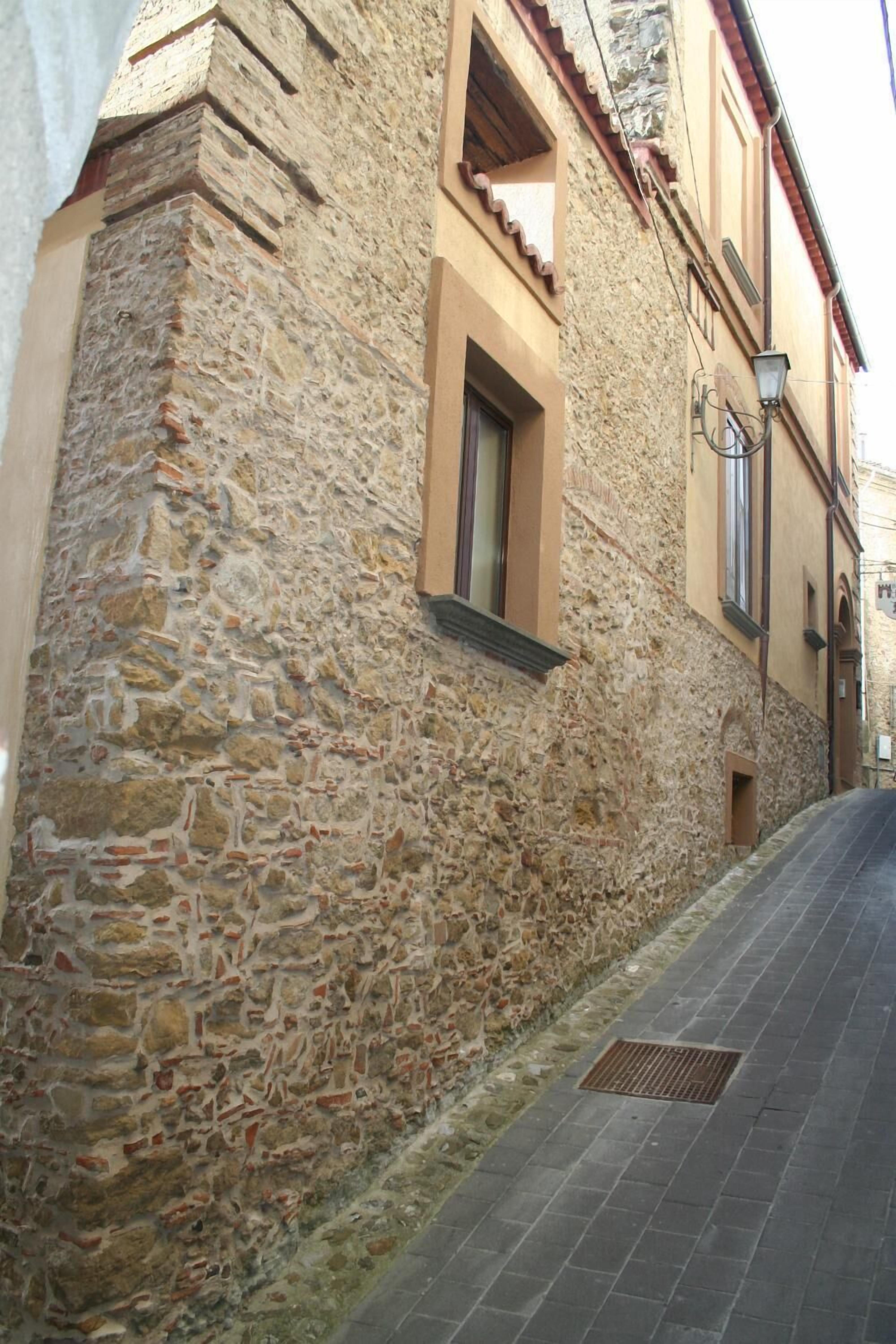 Uma rua de pedra estreita, com um edifício que apresenta uma janela e uma pequena porta.
