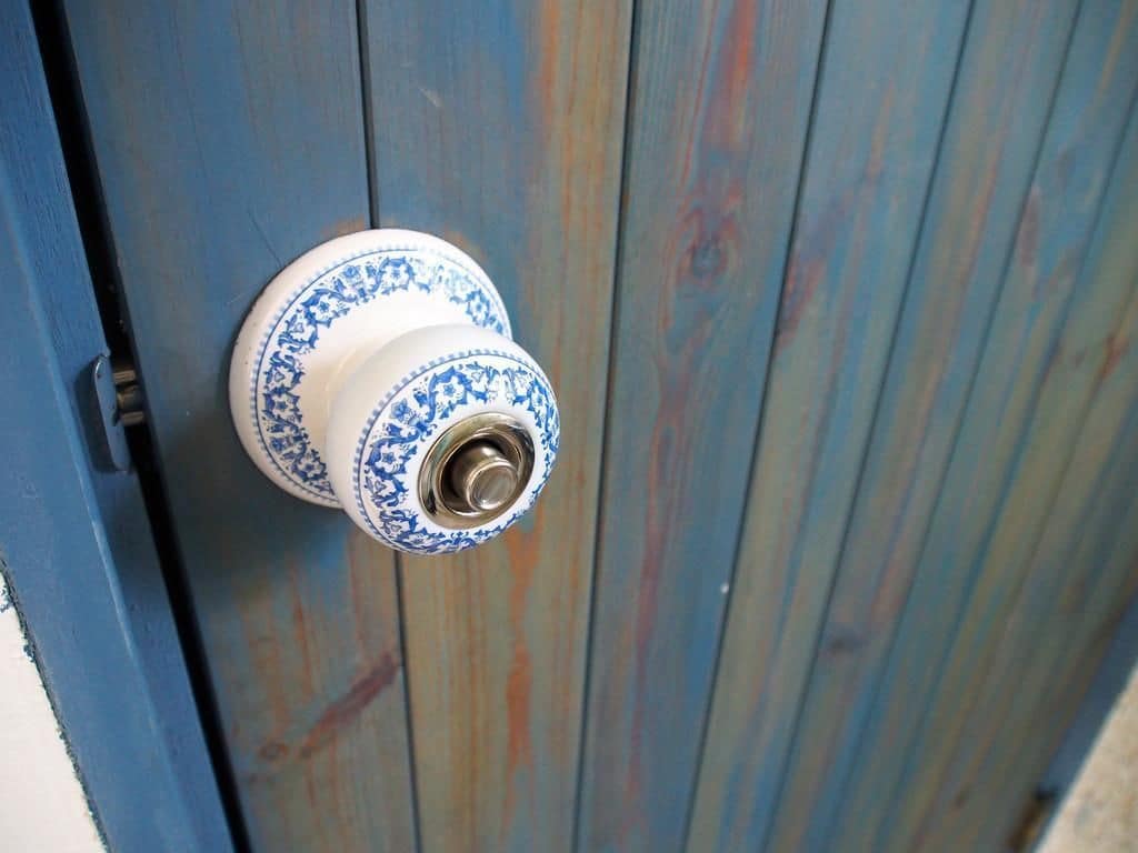 Uma porta azul com maçaneta de padrão azul e branco.