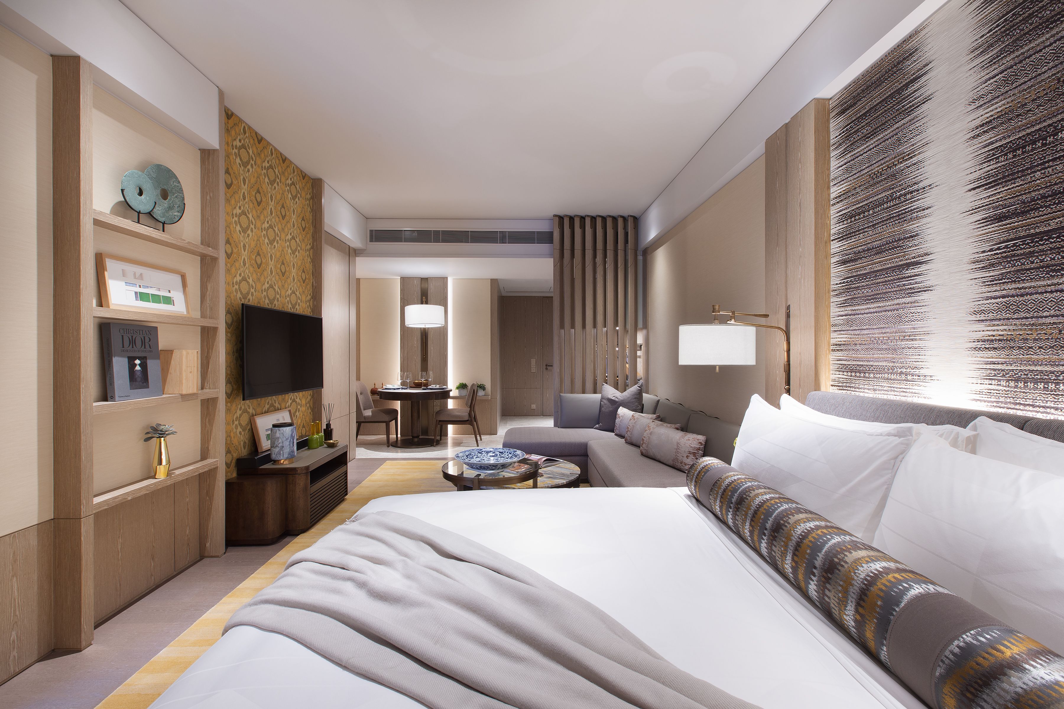 Quarto de hotel moderno com uma cama grande, um sofá, uma televisão e uma área de jantar.