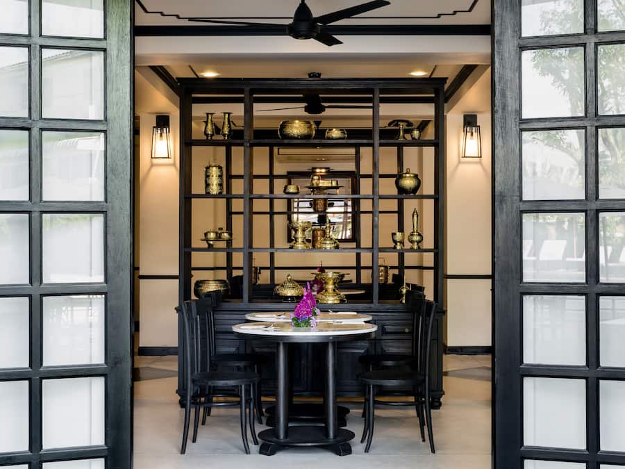 Uma sala de jantar com uma mesa redonda, cadeiras pretas e um objeto decorativo no centro.