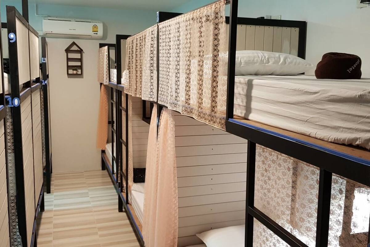 Um corredor estreito com beliches, cada um com uma cortina estampada.