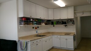 Uma cozinha compacta com armários brancos, pia e duas micro-ondas embutidas.
