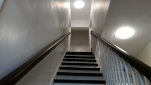 Uma escada estreita com corrimão em ambos os lados e um ponto de luz no topo.