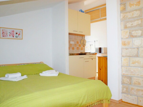 Um quarto com uma cama, uma cozinha compacta e um banheiro.