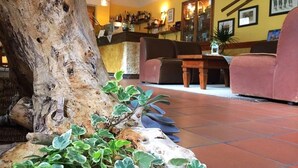 Um lobby com um tronco de árvore grande, área de bar e disposição de assentos.