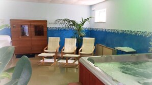 Um espaço de spa com hidromassagem, cadeiras de madeira, um armário de madeira e uma parede revestida de azulejos.