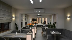 Interior moderno de restaurante com área de jantar central, cabines e um bar.