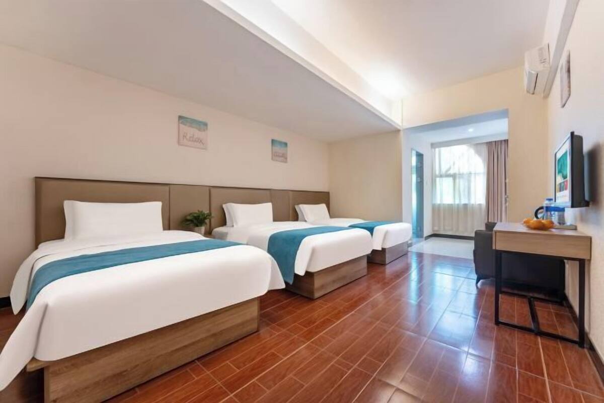 Quarto de hotel com duas camas, uma escrivaninha e uma televisão.