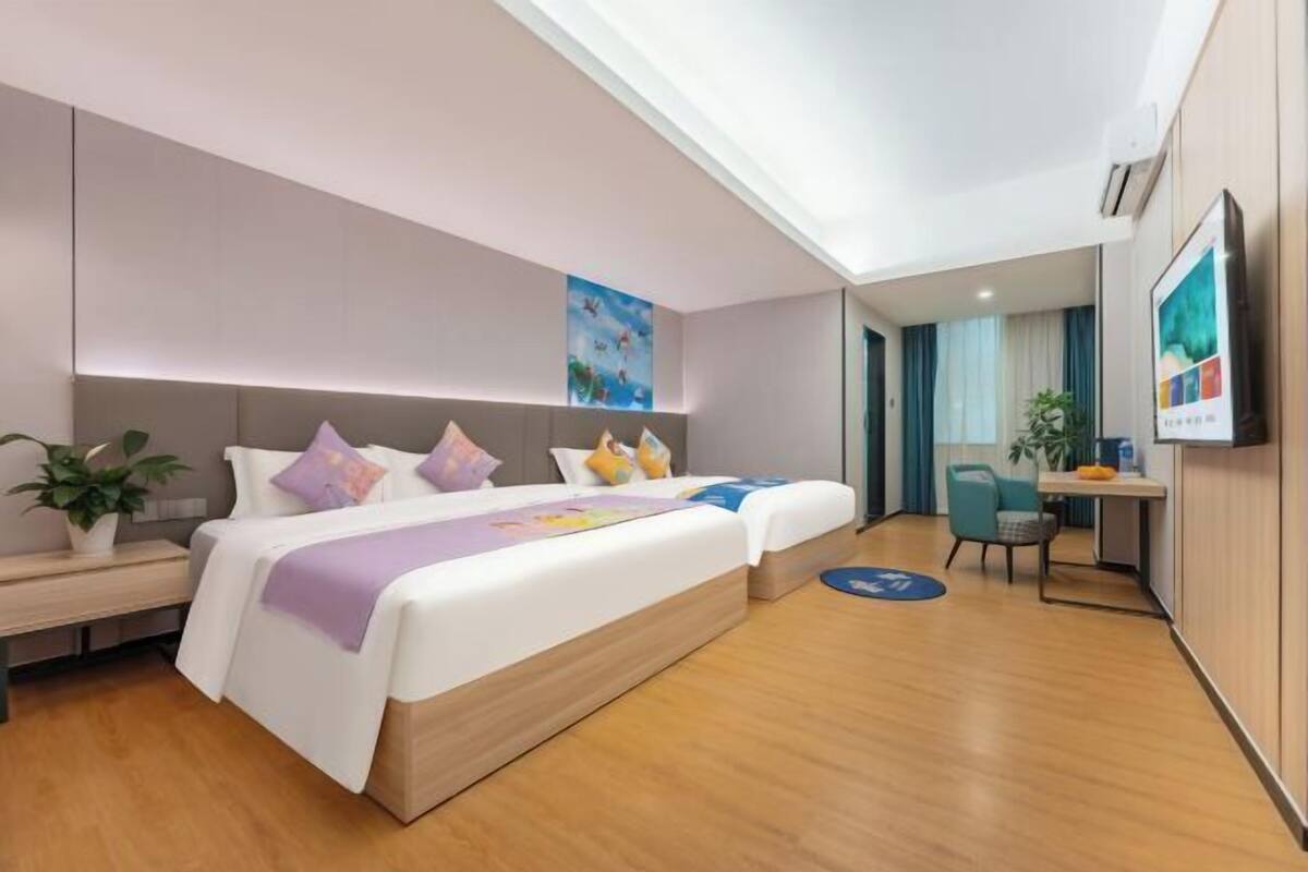 Quarto de hotel moderno com uma cama grande, uma escrivaninha, uma cadeira e uma televisão.