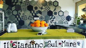 Uma mesa com toalha verde, uma tigela de laranjas e uma placa com o texto 'il Giardino Sul Mare'.