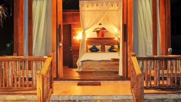 Uma cabana de madeira com cama, cortinas e uma escadaria de pedra.