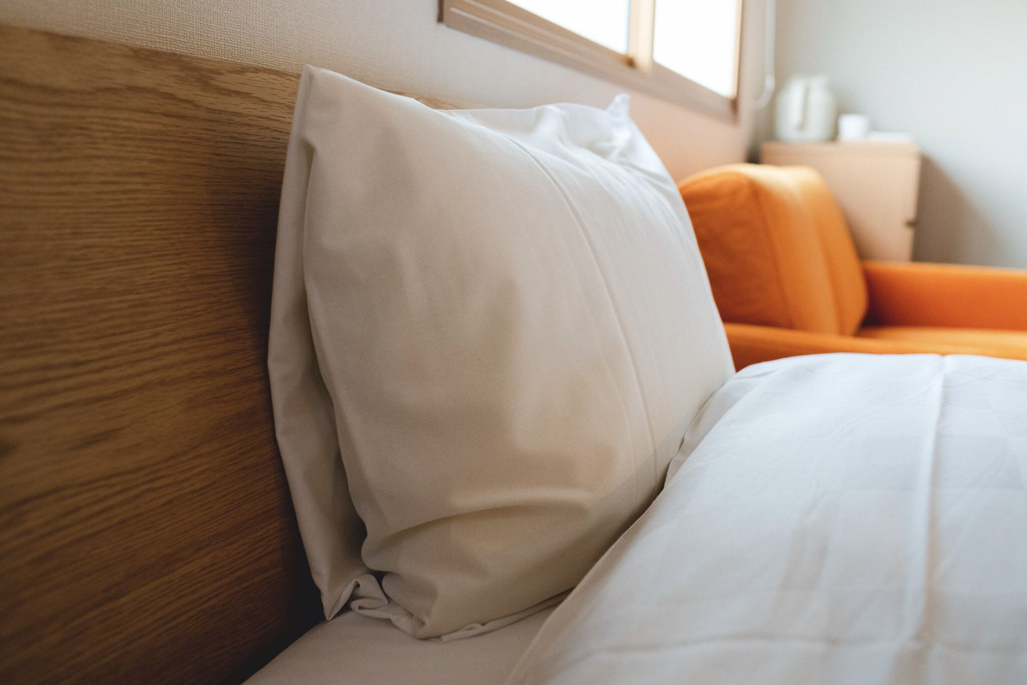 Uma cama com cabeceira de madeira e roupa de cama branca.