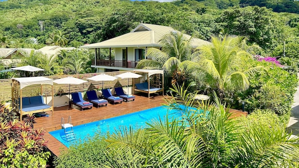 Resort com piscina, espreguiçadeiras e vista para montanhas exuberantes.