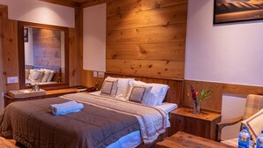 Quarto com painéis de madeira, uma cama grande, mesas de cabeceira, um espelho e um quadro na parede.