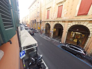 Vista da rua com carros estacionados, um prédio com loja no térreo e uma calçada para pedestres.