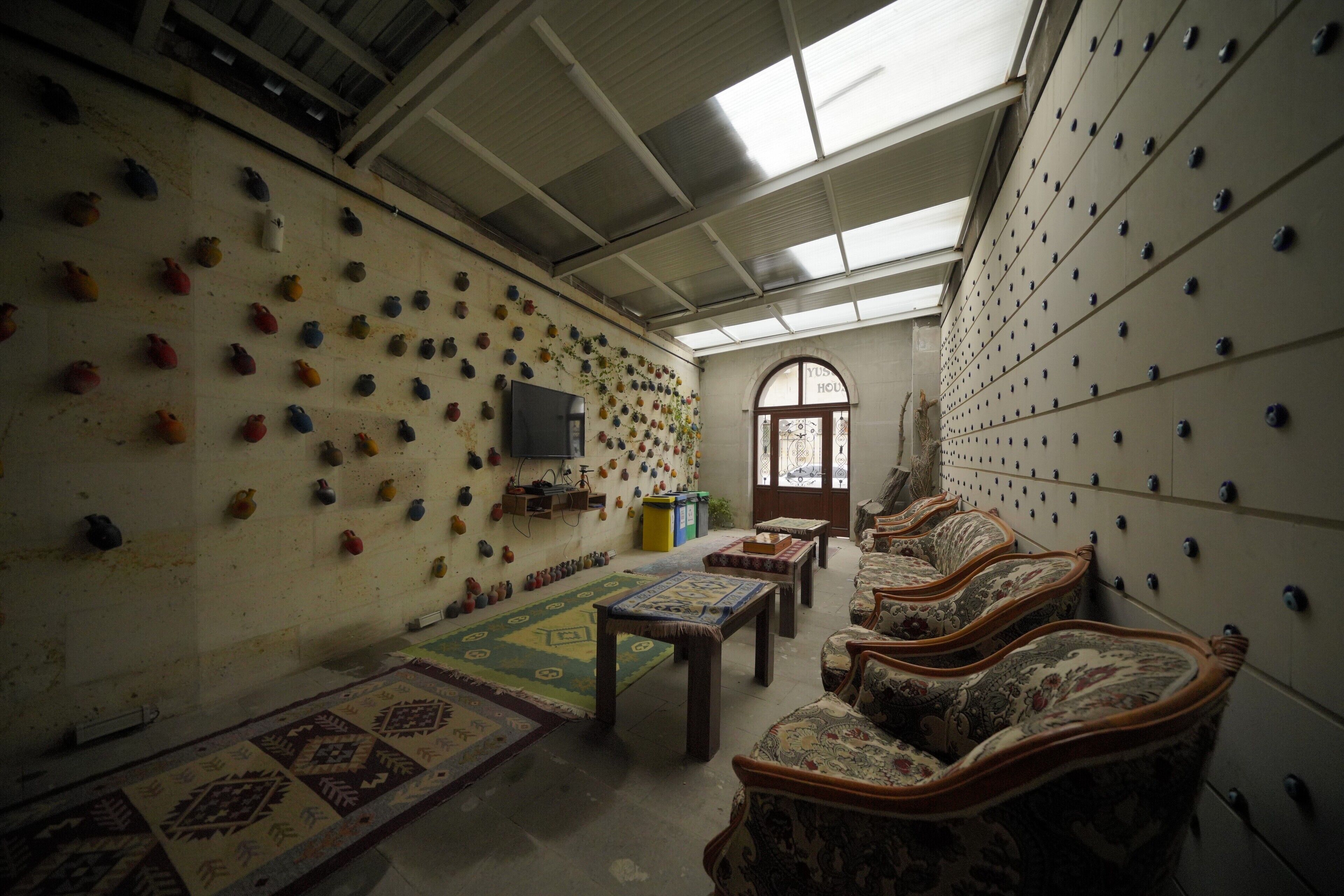 Quarto com paredes para escalada, televisão e tapetes estampados.