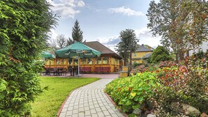 Restaurante com mesas ao ar livre e um caminho de tijolos que o leva até ele.