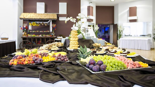 Mesa de buffet com diversas frutas e sobremesas.