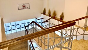 Escada com guarda-mão de madeira e balaústres de metal, conduzindo a um nível inferior. Uma placa na parede diz 'Sweet Dream Accommodations'.
