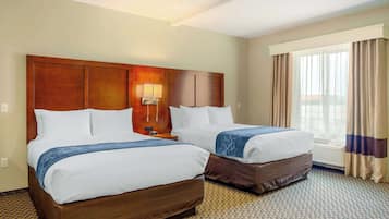 Quarto de hotel com duas camas, cabeceira de madeira, mesa de cabeceira, abajur e janela com cortinas.