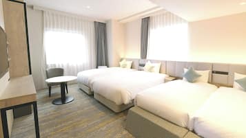 Quarto de hotel com duas camas, uma mesa redonda pequena e uma cadeira.