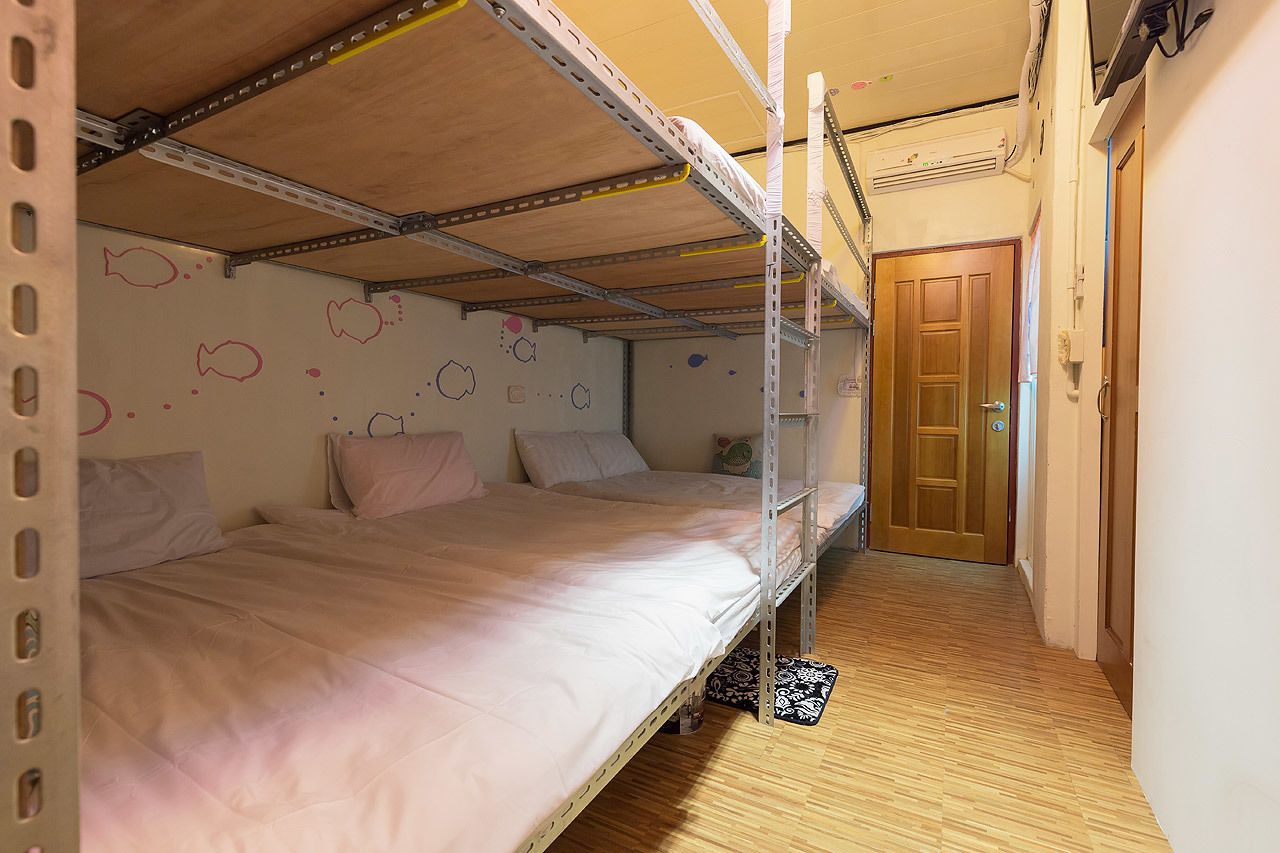 Quarto com beliche, chão de madeira, uma porta e parede decorada com corações.