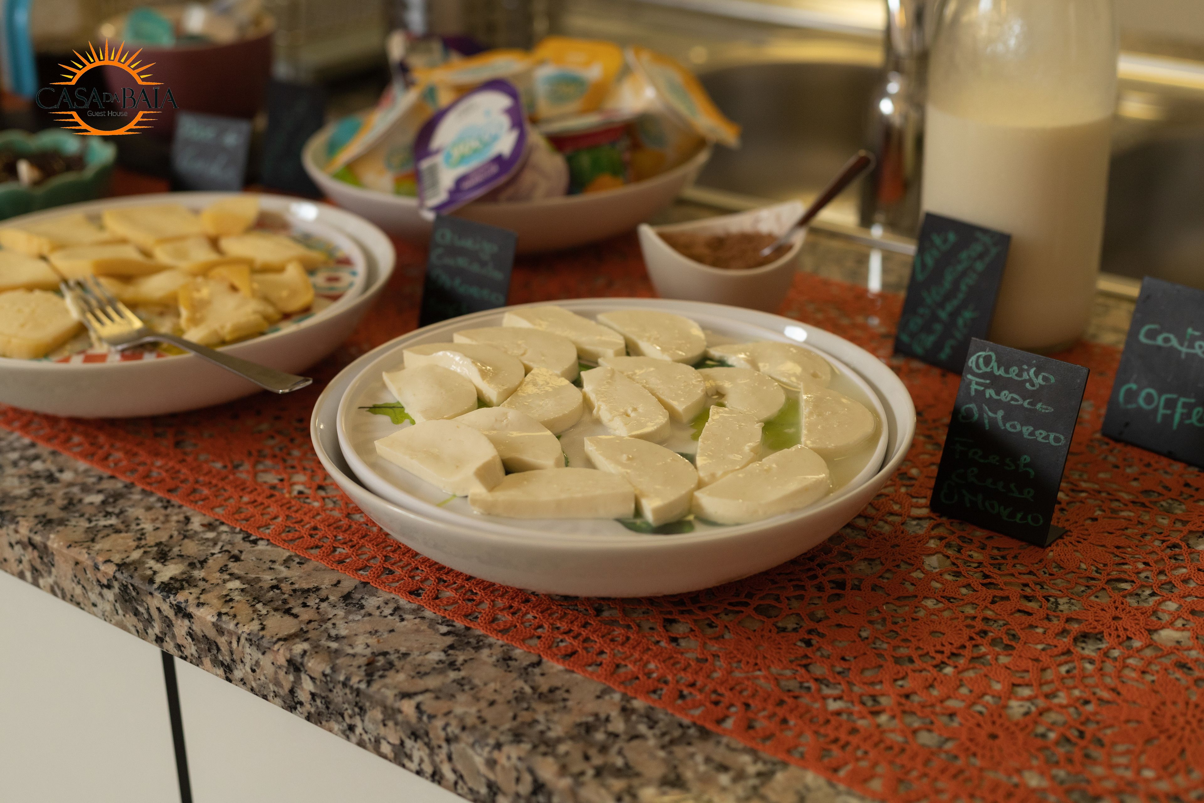 Buffet com diversos pratos, incluindo tofu, queijo e café.