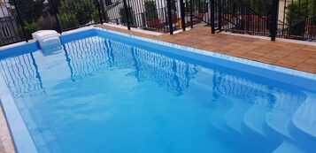 Piscina retangular com um deck de madeira ao redor.