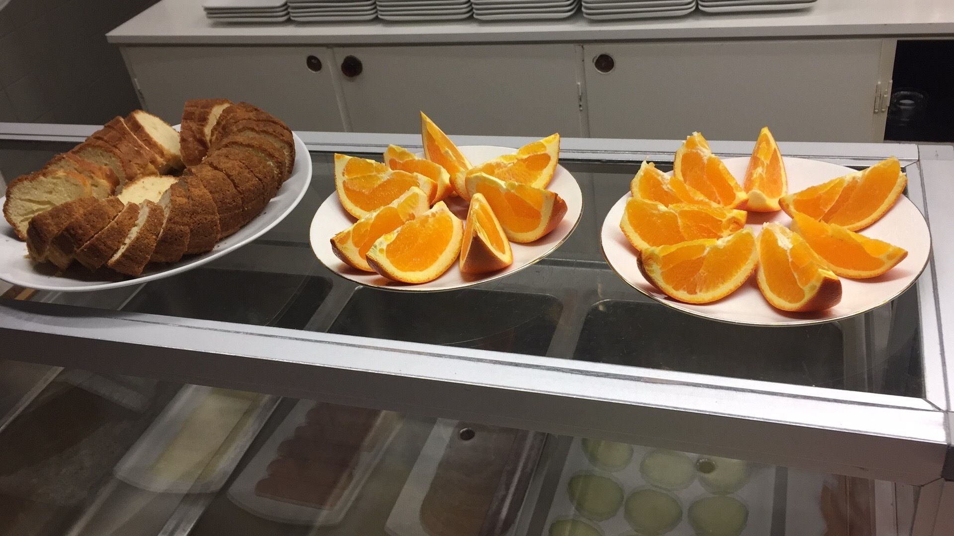 Um balcão de buffet com pão fatiado e laranjas.